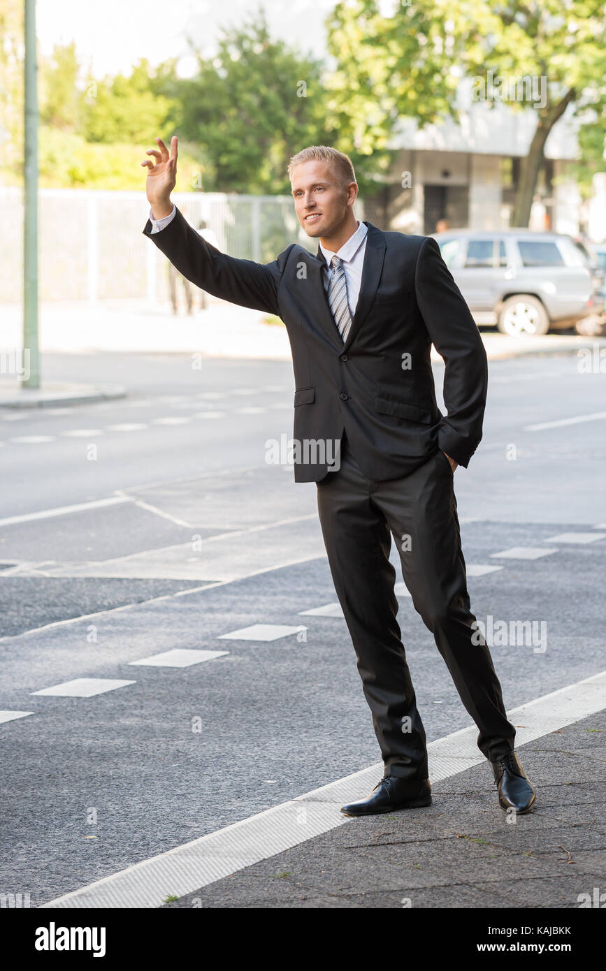 Young Businessman Calling Taxi On The Street Stock Photo - Alamy