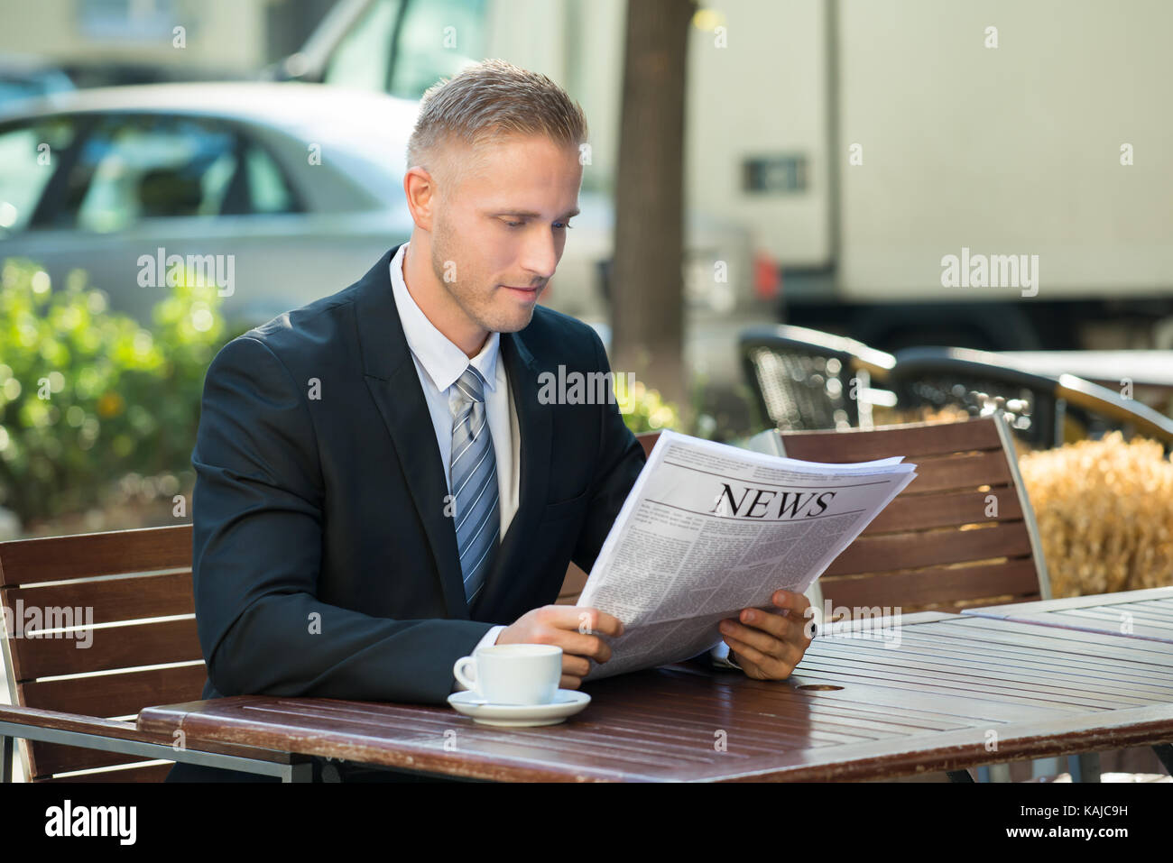 Photo Of Businessman Sitting In Cafe Reading Newspaper Stock Photo - Alamy