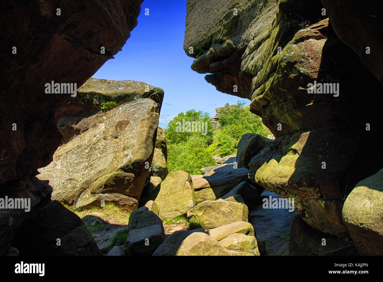 Opening through a large rock formation with trees in the backround at ...