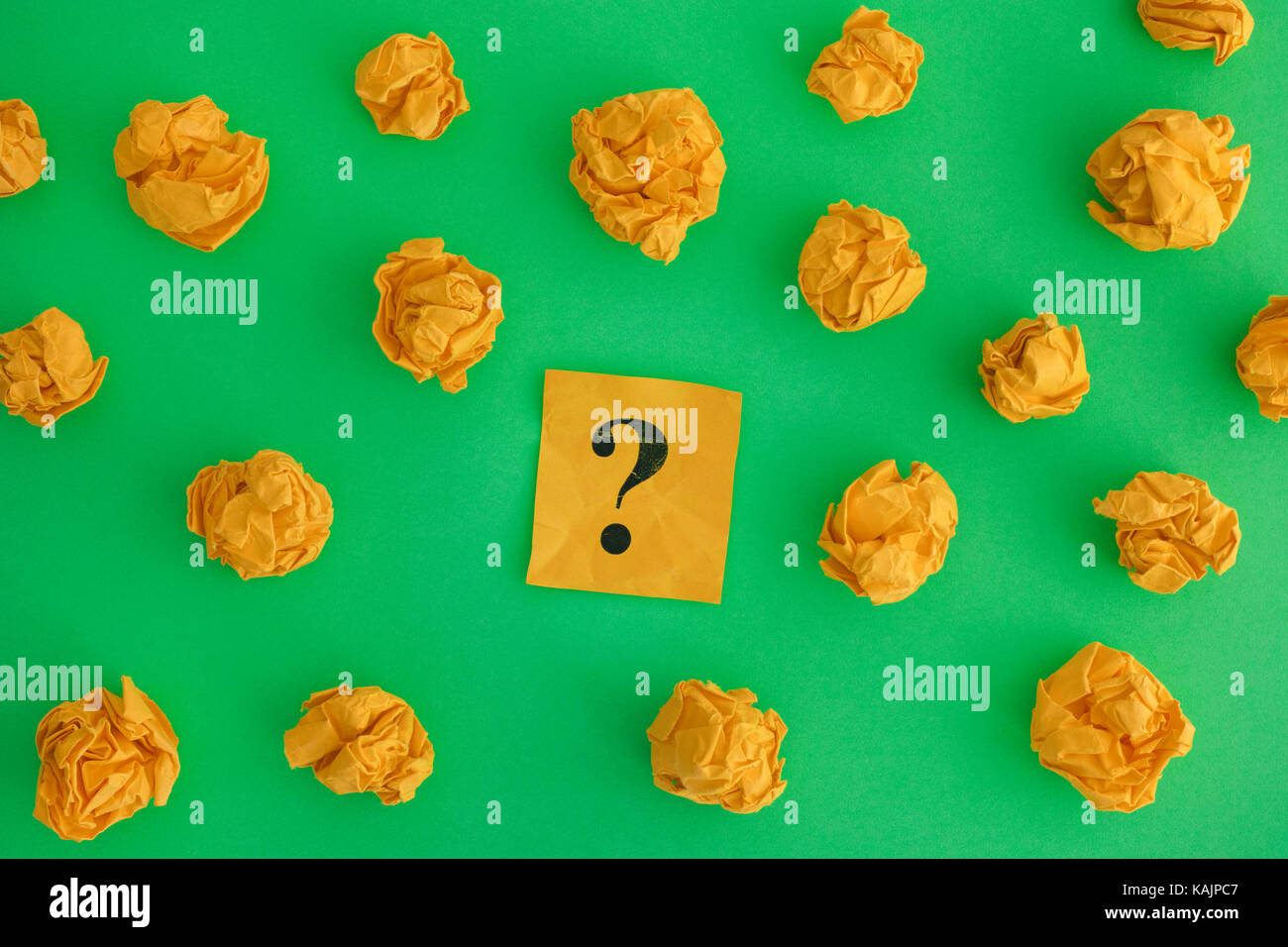 Yellow crumpled paper balls and question mark on a green background ...