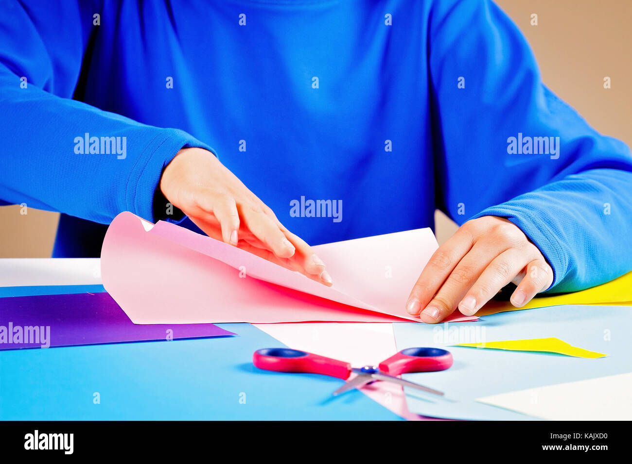 Kid folding colored paper and making origami Stock Photo - Alamy