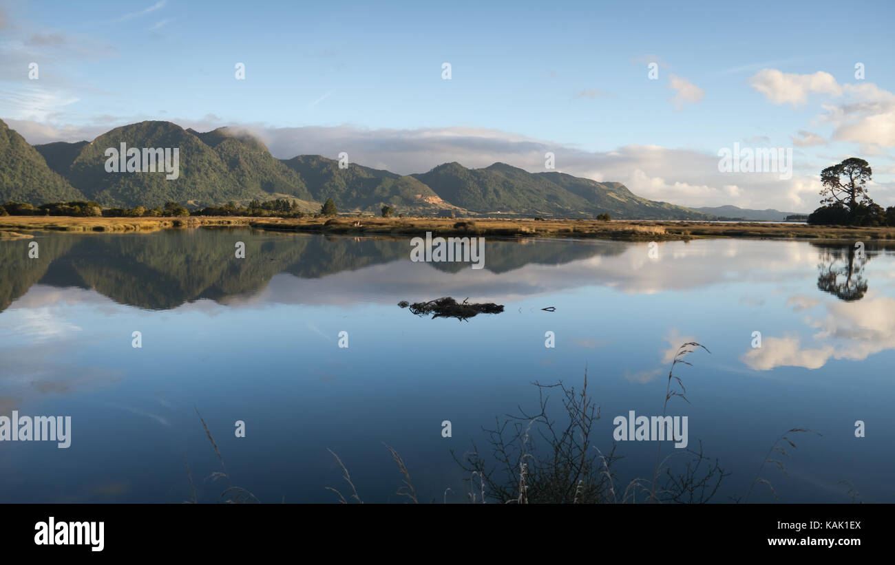 Beautiful mirror like reflection of the hills in the Aorere River Inlet ...