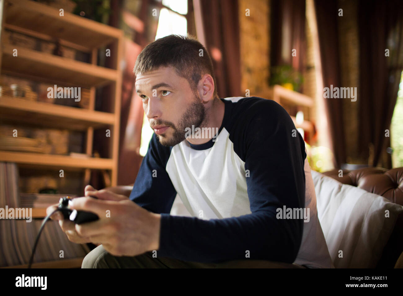 Side view of handsome young man holding game controller, playing video ...