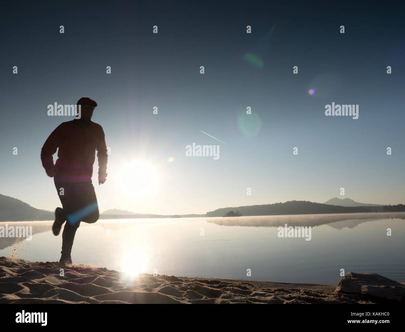 Tall fit man running fast by the sea on the beach. Powerful runner ...