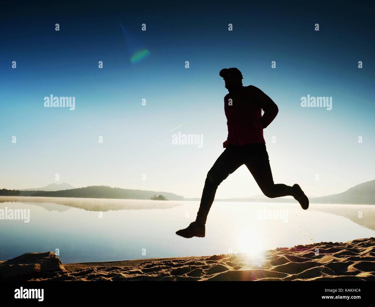 Tall fit man running fast by the sea on the beach. Powerful runner ...
