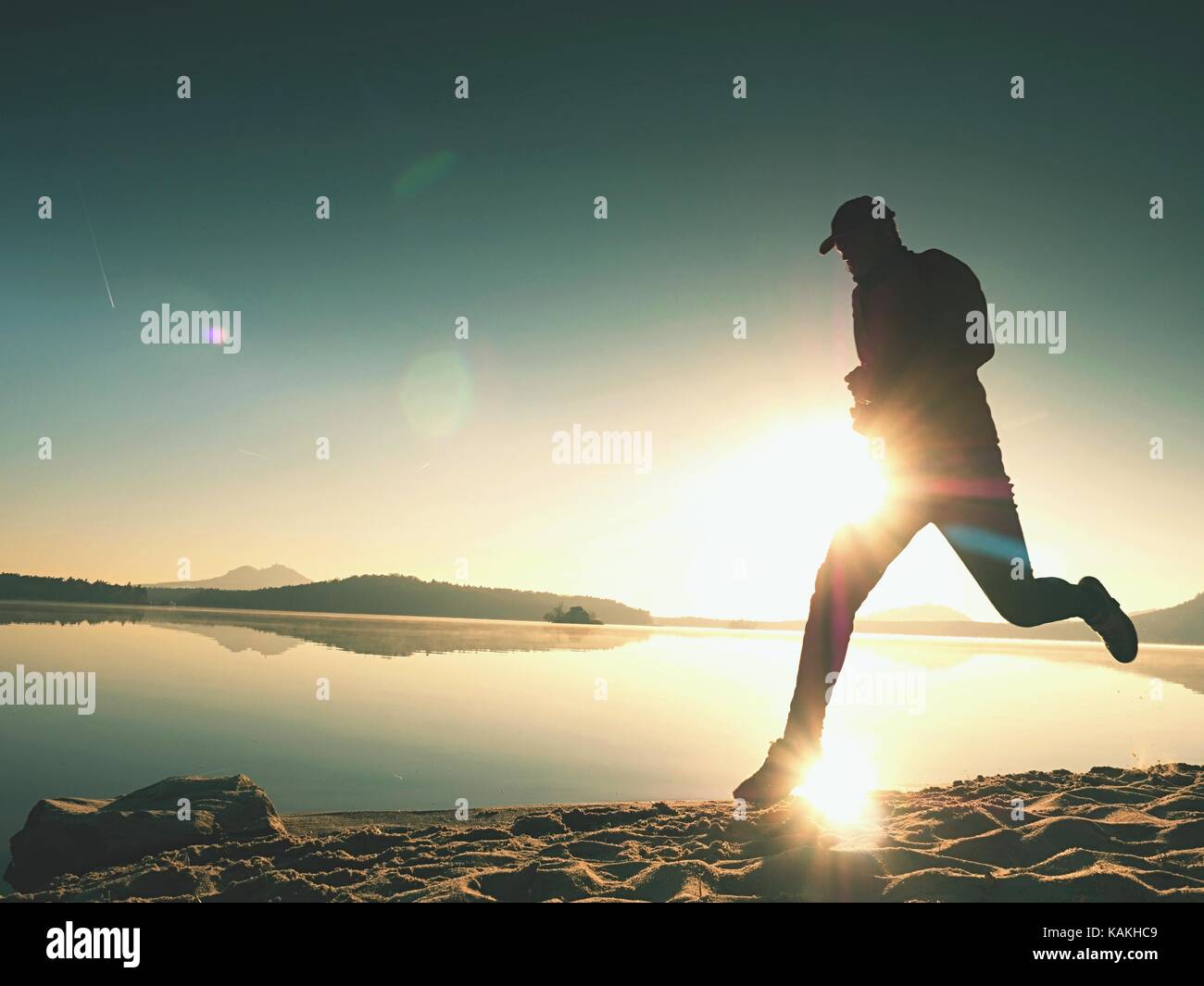 Tall fit man running fast by the sea on the beach. Powerful runner ...
