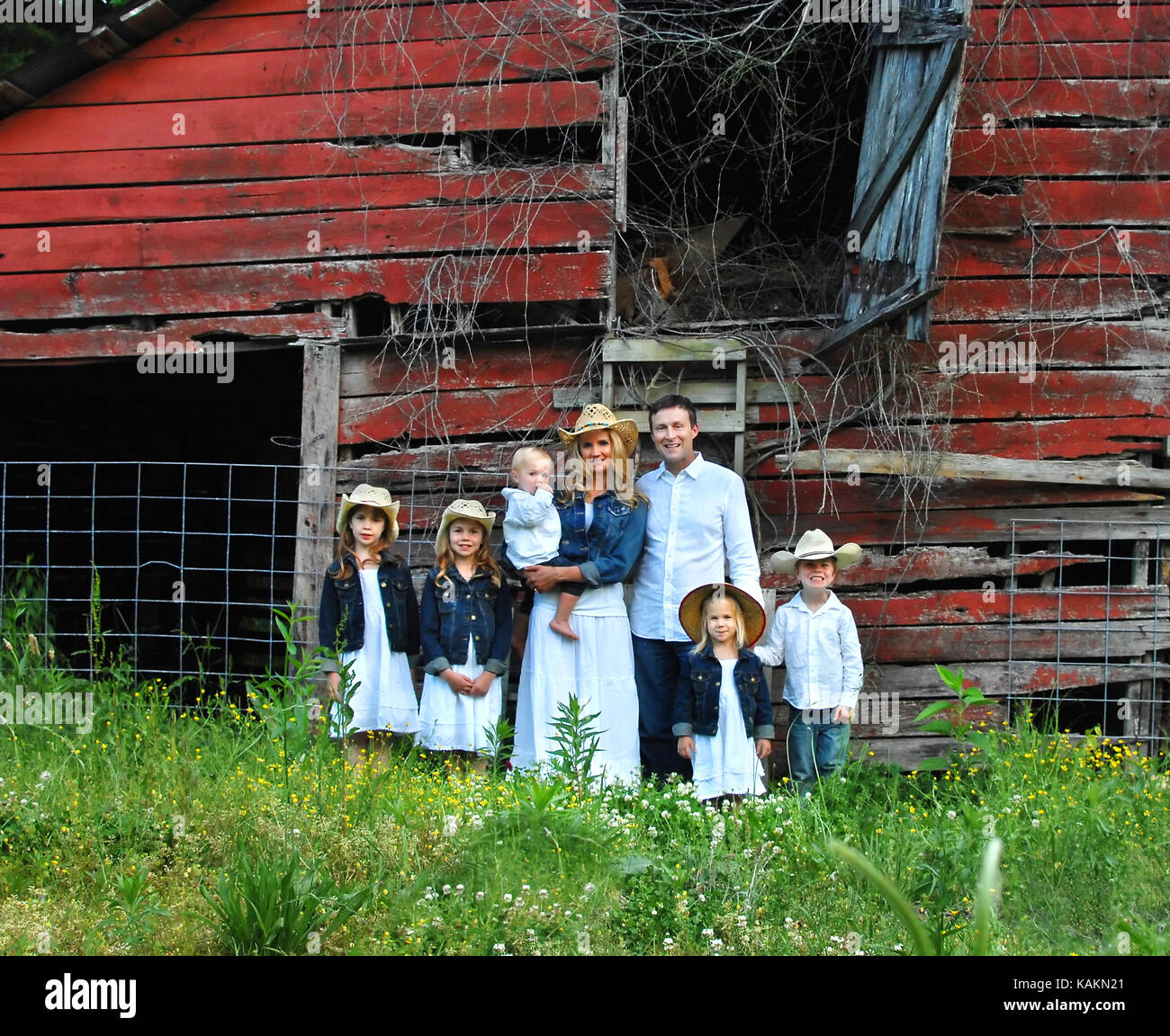 Father and mother pose with their five children in front of a rustic ...