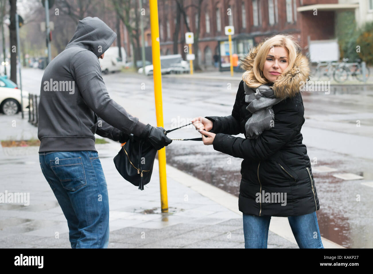 Male robber pulling purse from woman on sidewalk during winter Stock ...