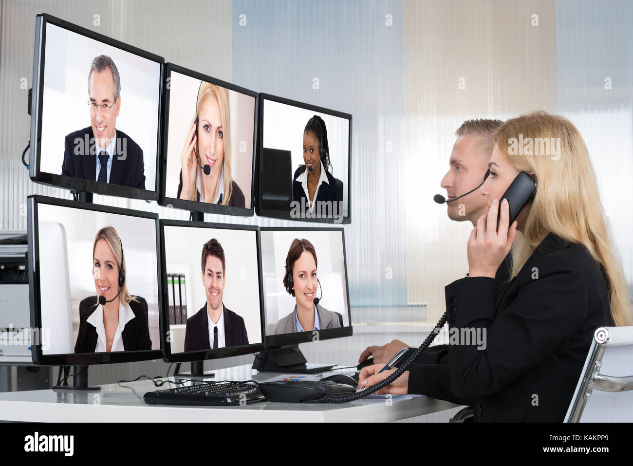 Business people having conference call with multiple computer screens ...