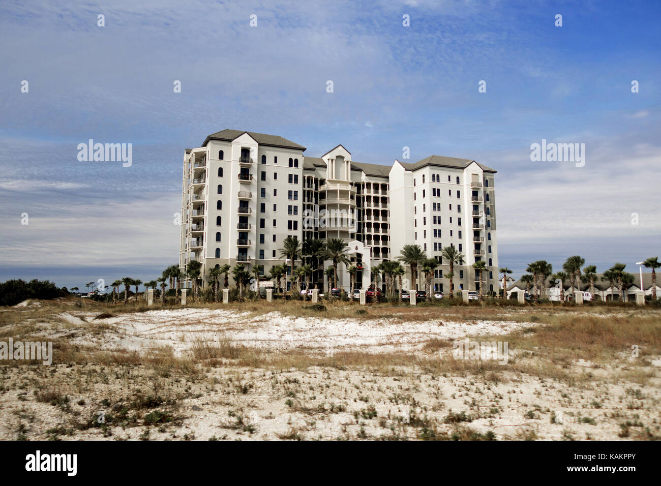 A white high rise condos building surrounded by palm trees on a bright ...