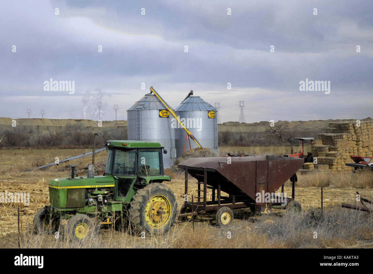 An old john Deere tractor with a rusty grain trailer in front of a ...