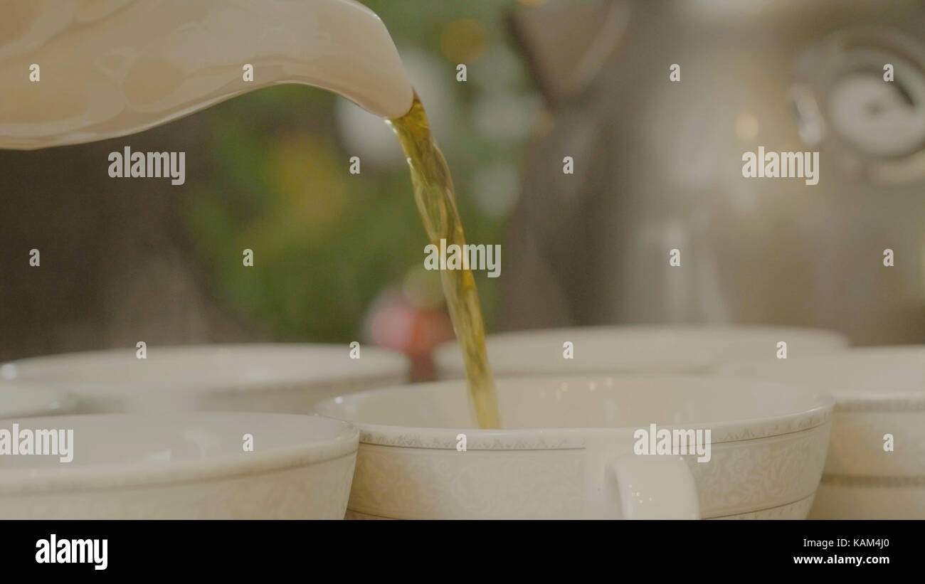 Tea being poured into tea cup. Kettle pours tea into cups Stock Photo ...