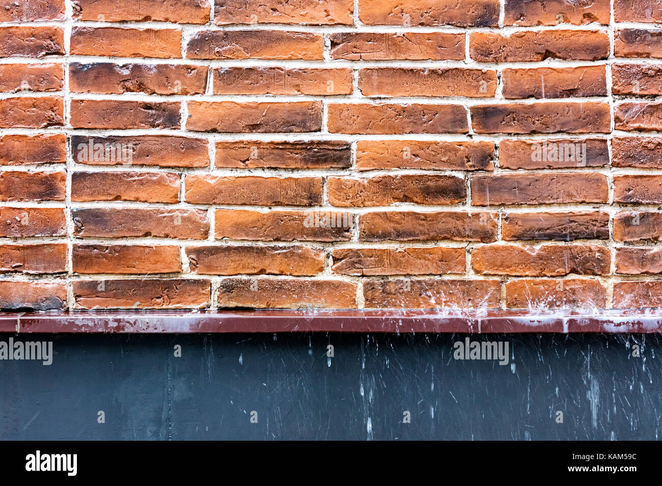 heavy rain in the city. surface of red brick wall with raindrops ...