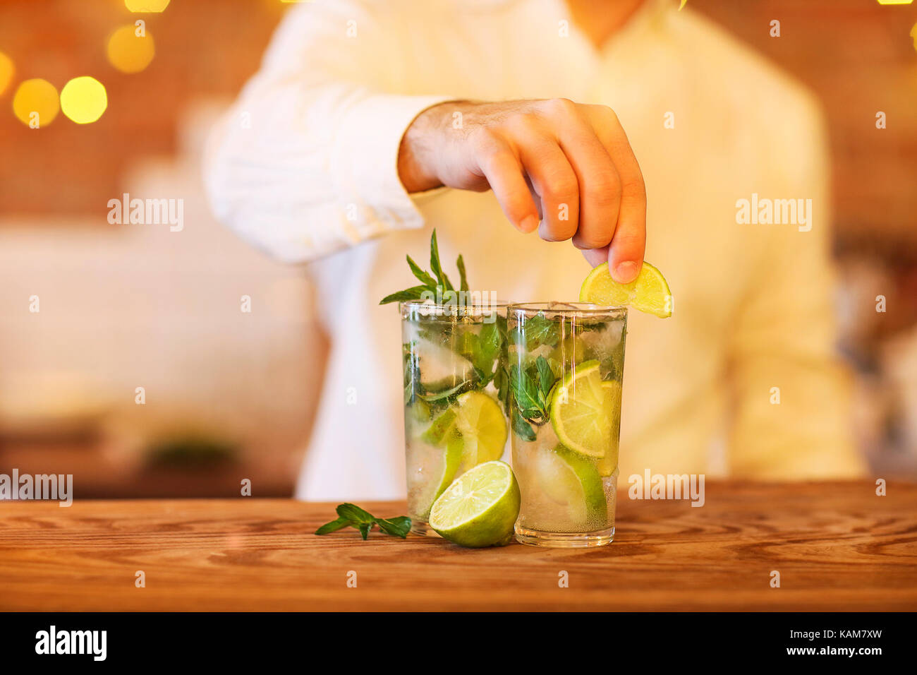 Bartender making two mojito cocktails on wooden bar counter Stock Photo - Alamy