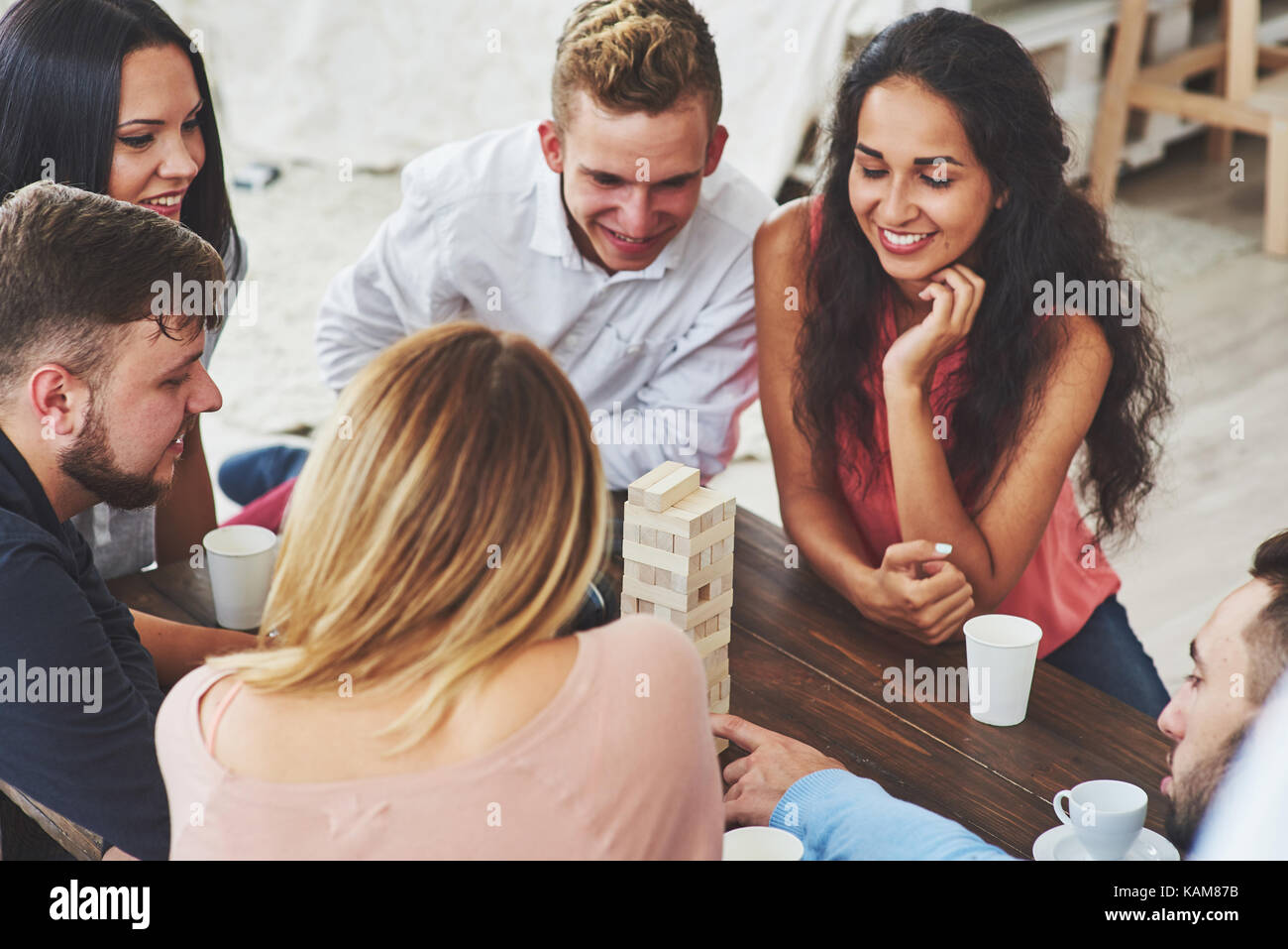 Group of creative friends sitting at wooden table. People having fun ...