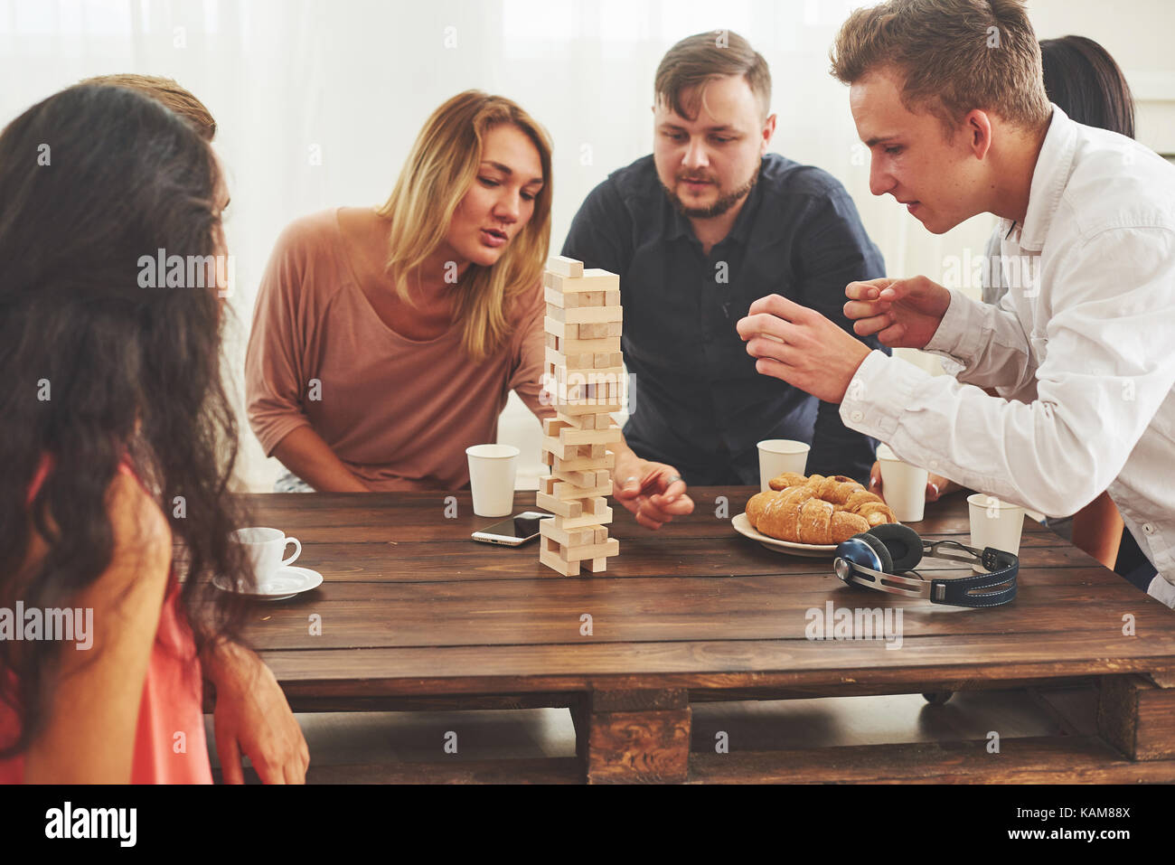 Group of creative friends sitting at wooden table. People having fun ...