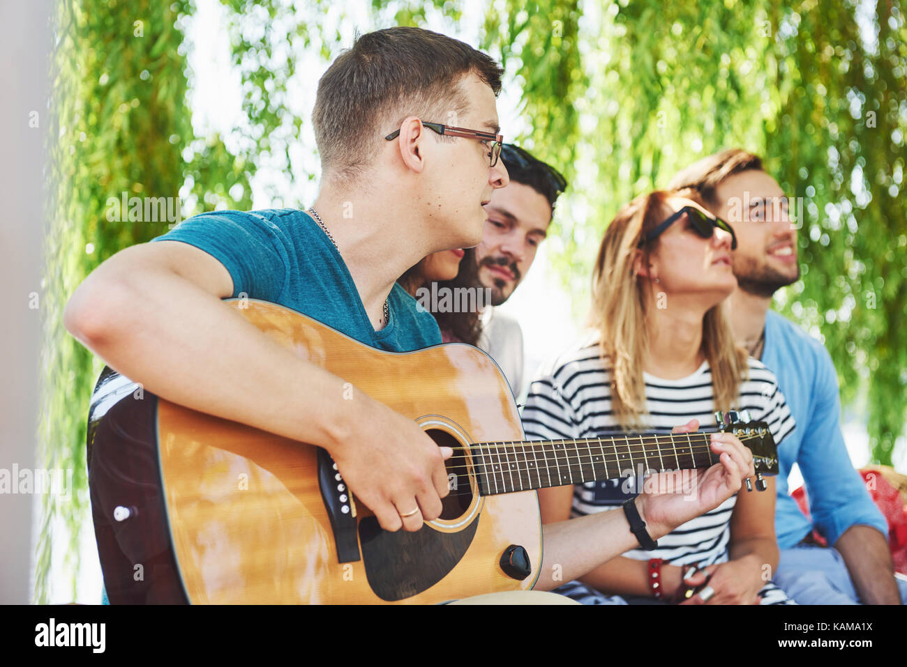 Group of happy friends with guitar. While one of them is playing guitar ...