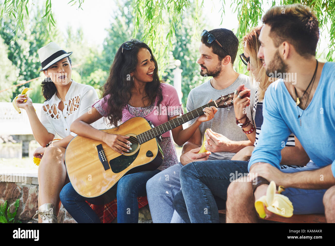 Group of happy friends with guitar. While one of them is playing guitar ...