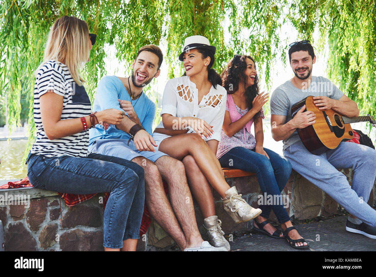 Group of happy friends with guitar. While one of them is playing guitar ...