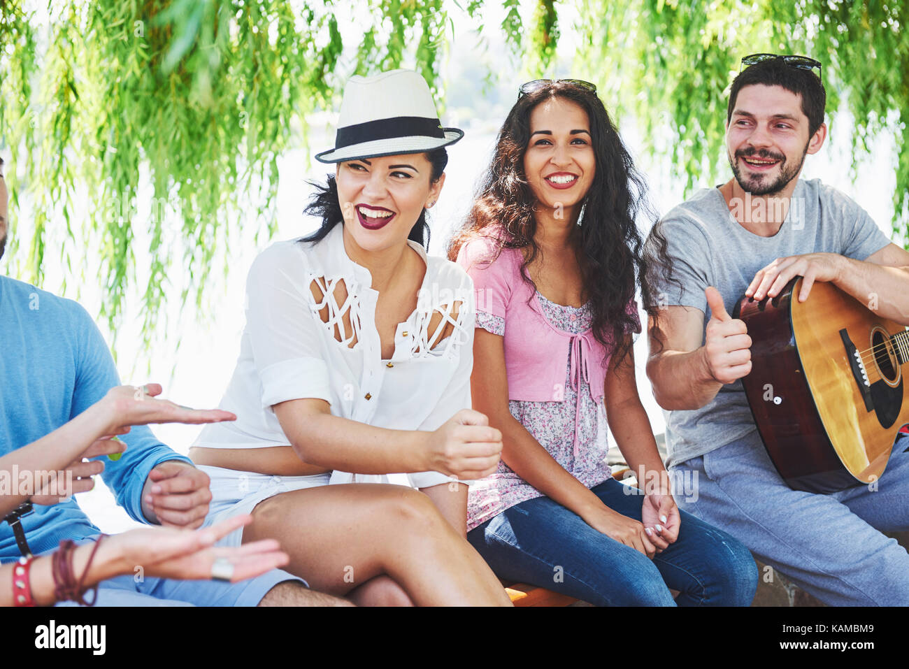 Group of happy friends with guitar. While one of them is playing guitar ...