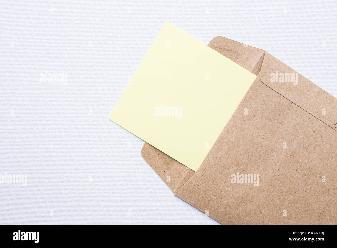 Yellow notepad in the envelope on white canvas background Stock Photo ...