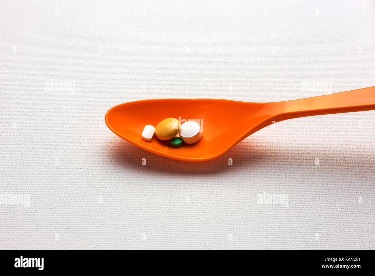 Colorful pills on a spoon on white canvas background Stock Photo - Alamy