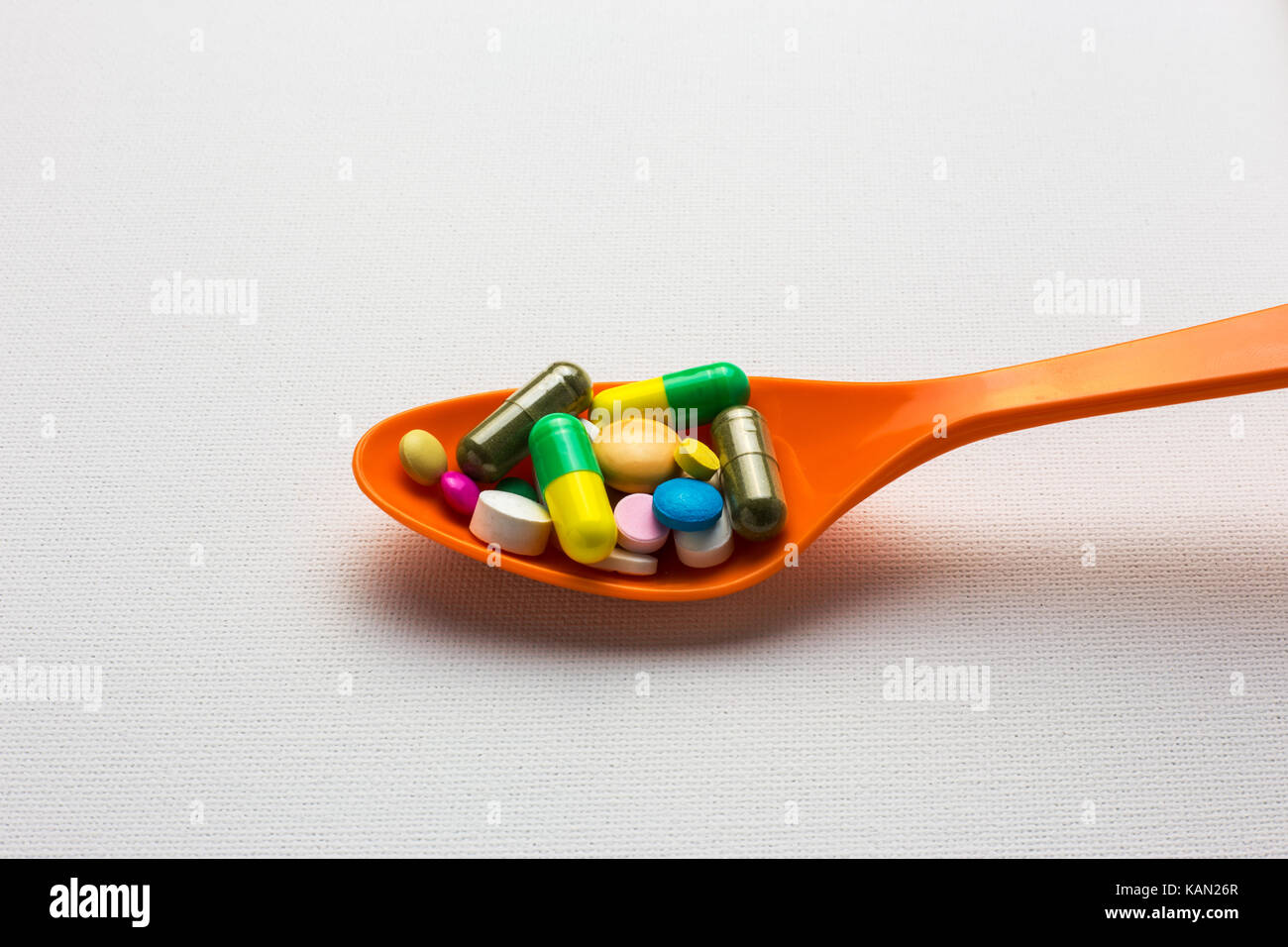 Many colorful pills on a spoon on white canvas background Stock Photo ...