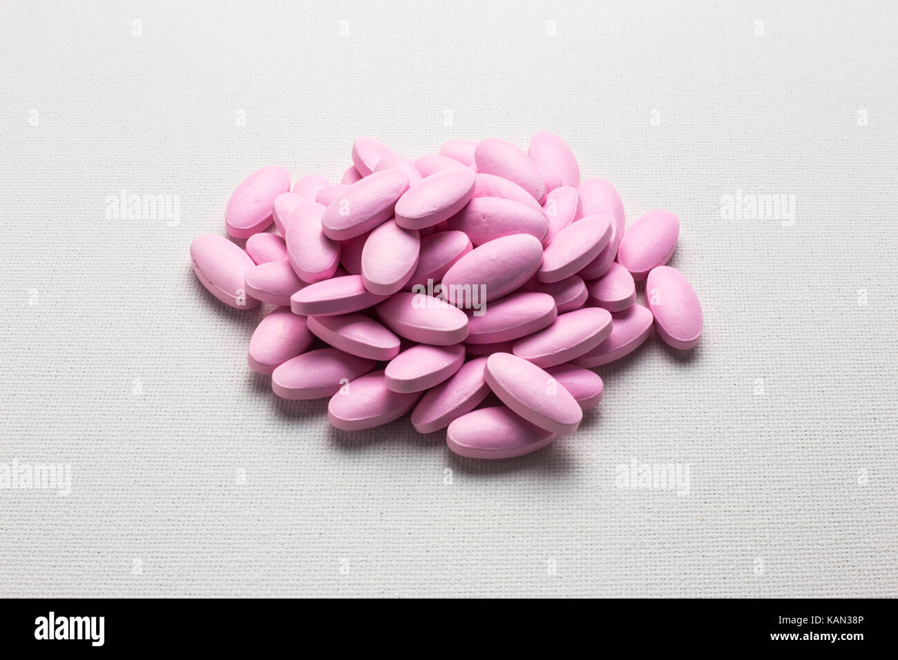 Many pink tablets pills on white canvas background Stock Photo - Alamy