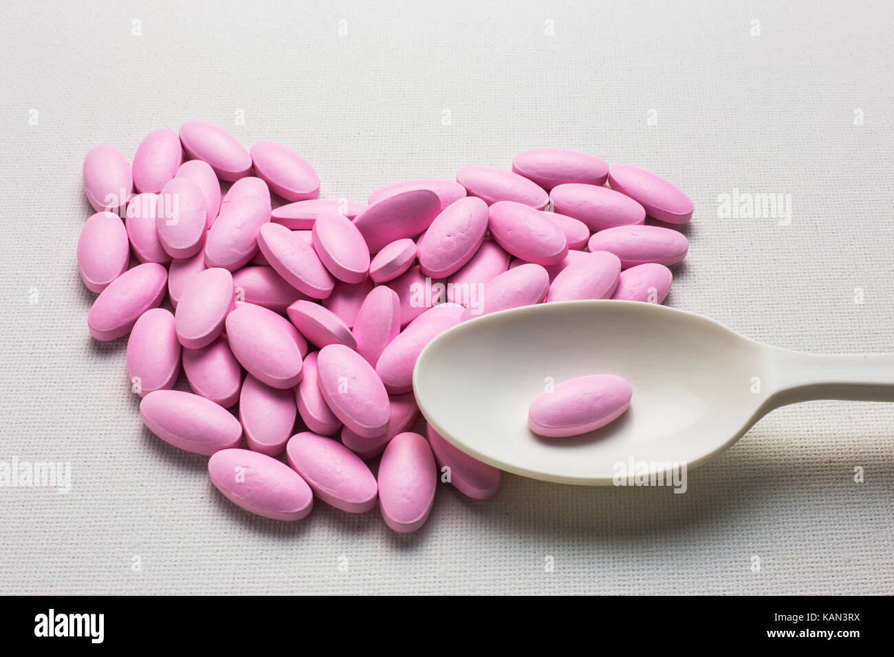 Many pink tablets pills in heart shape on white canvas background Stock ...