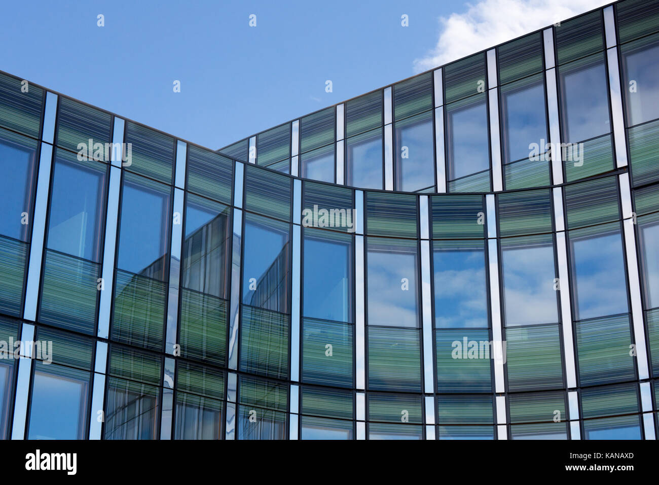 Office building with shiny blue glass and green facade on a sunny day ...