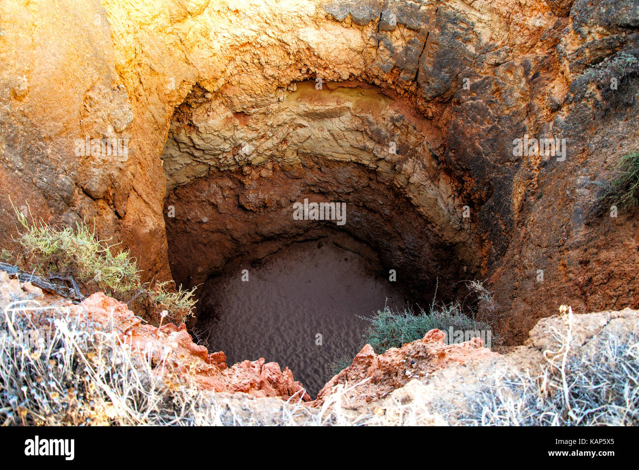 Deep round funnel among the rocks Stock Photo - Alamy