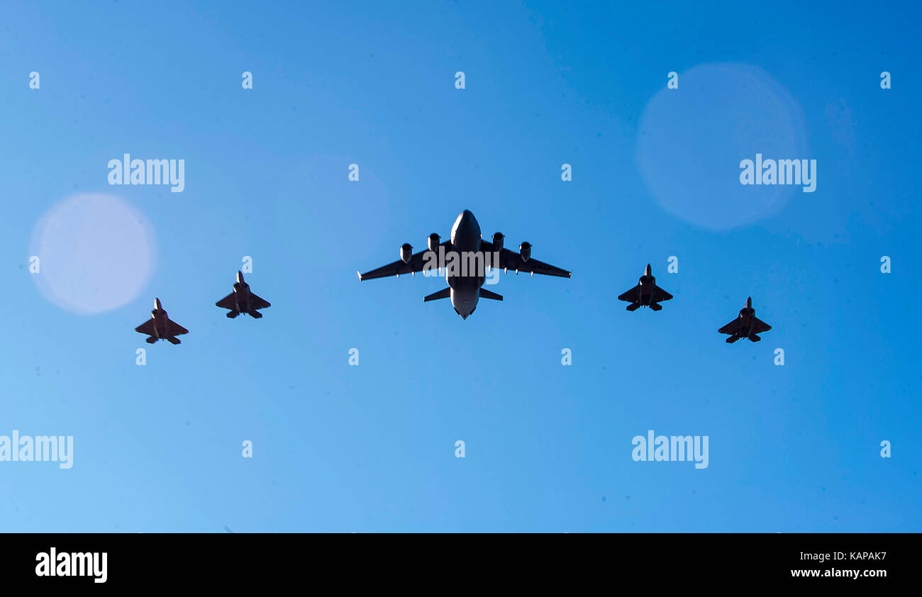 A C-17 Globemaster III and four F-22 Raptors fly in formation over ...