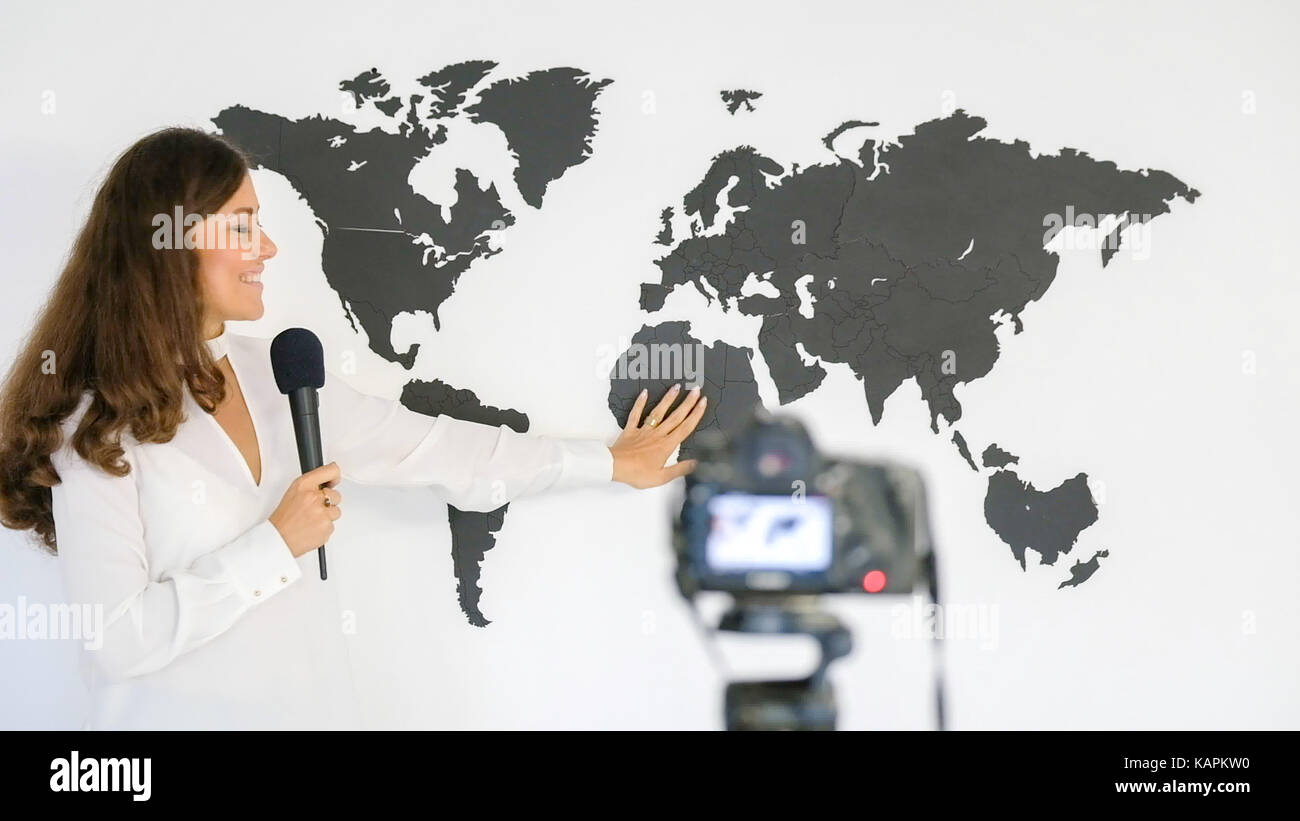 The journalist is reporting on the background of a large map of the ...