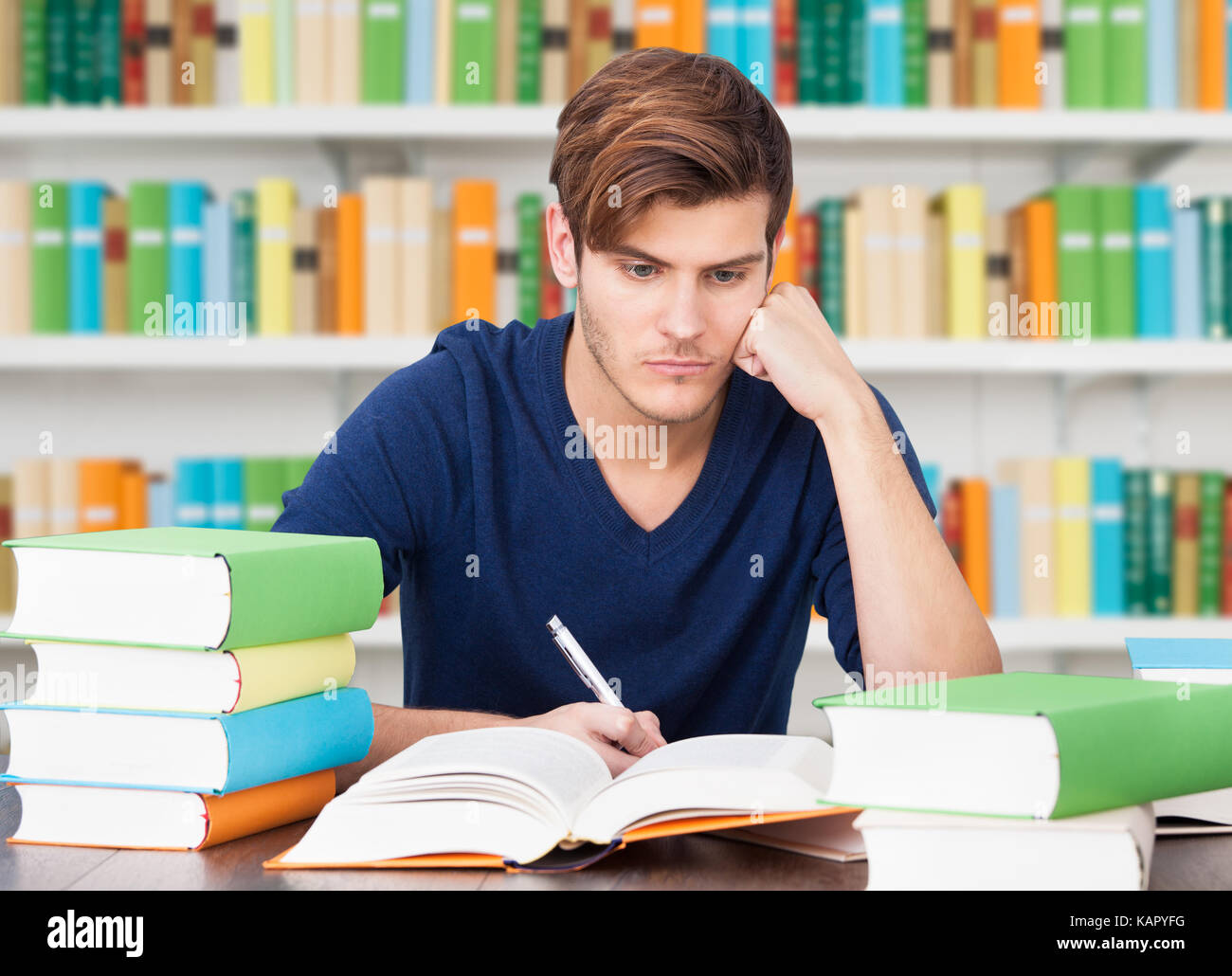 Concentrated young university student studying at desk in library Stock ...