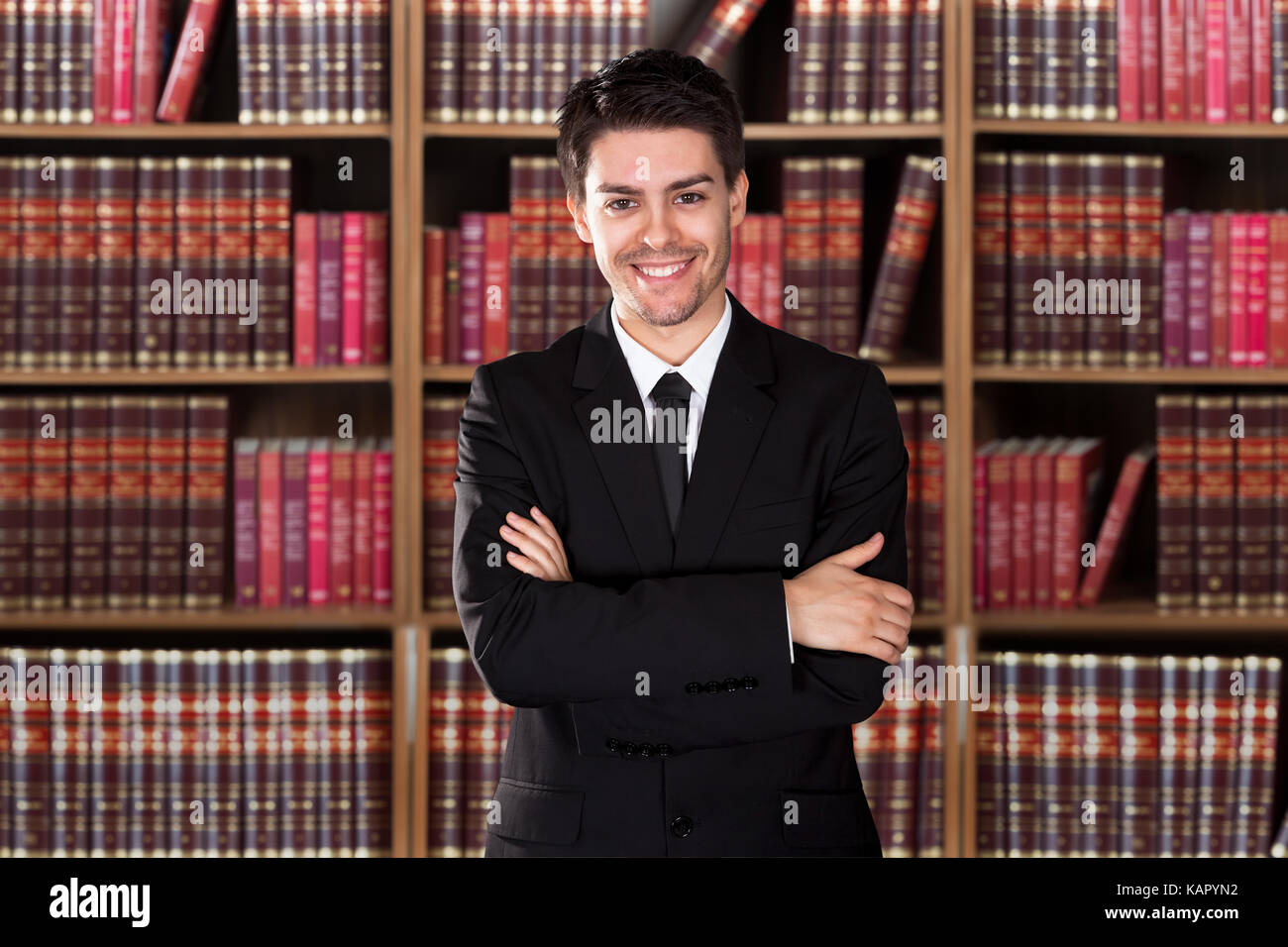 Portrait of confident male lawyer standing arms crossed against ...