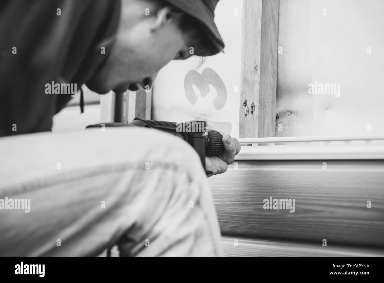 A worker installs panels beige siding on the facade of the house Stock ...