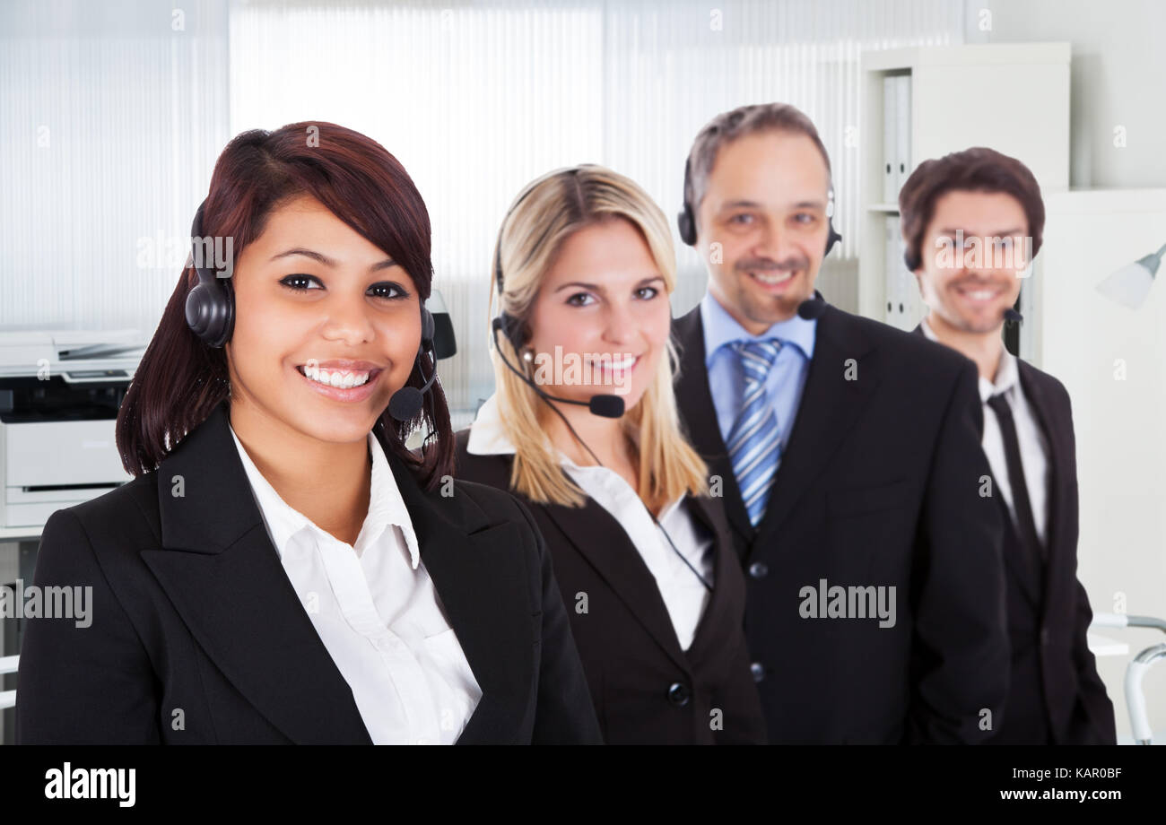 Portrait of confident call center representatives smiling in office ...