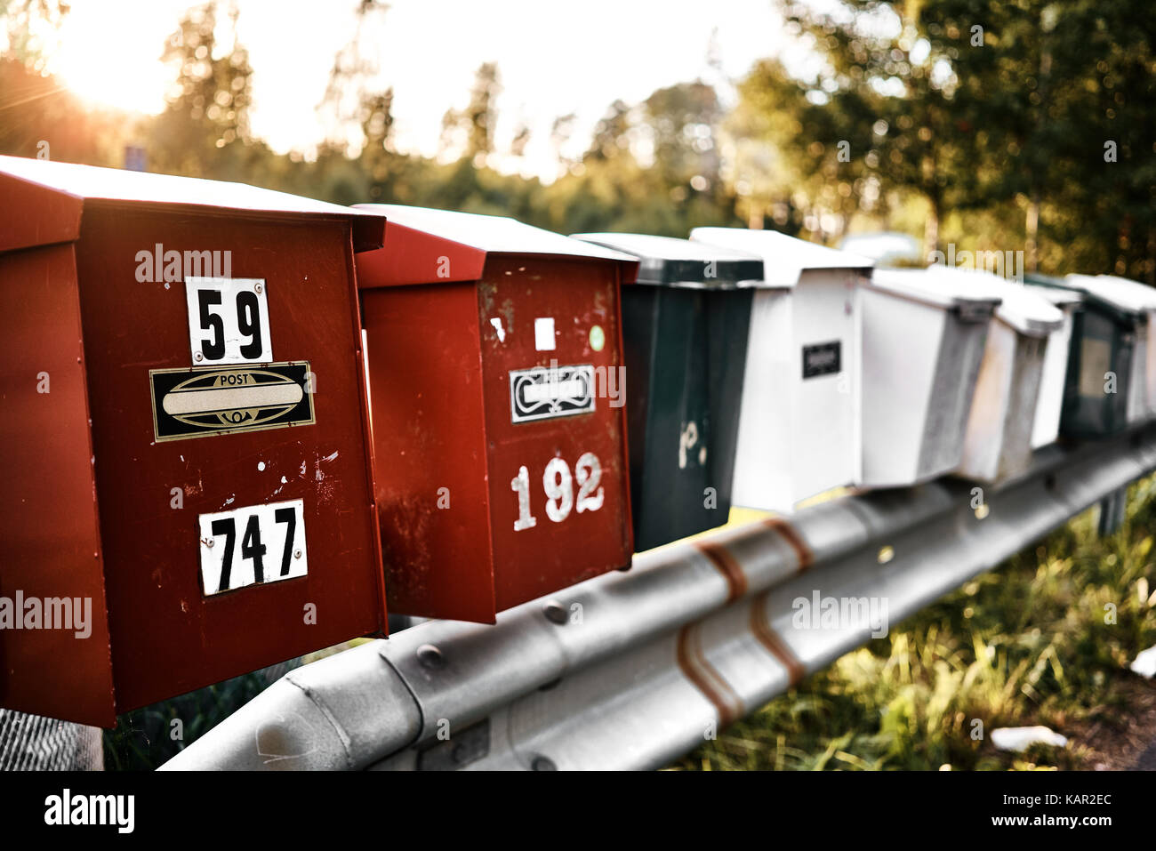 Old red mailbox with numbers in a row with sunlight and trees in the ...
