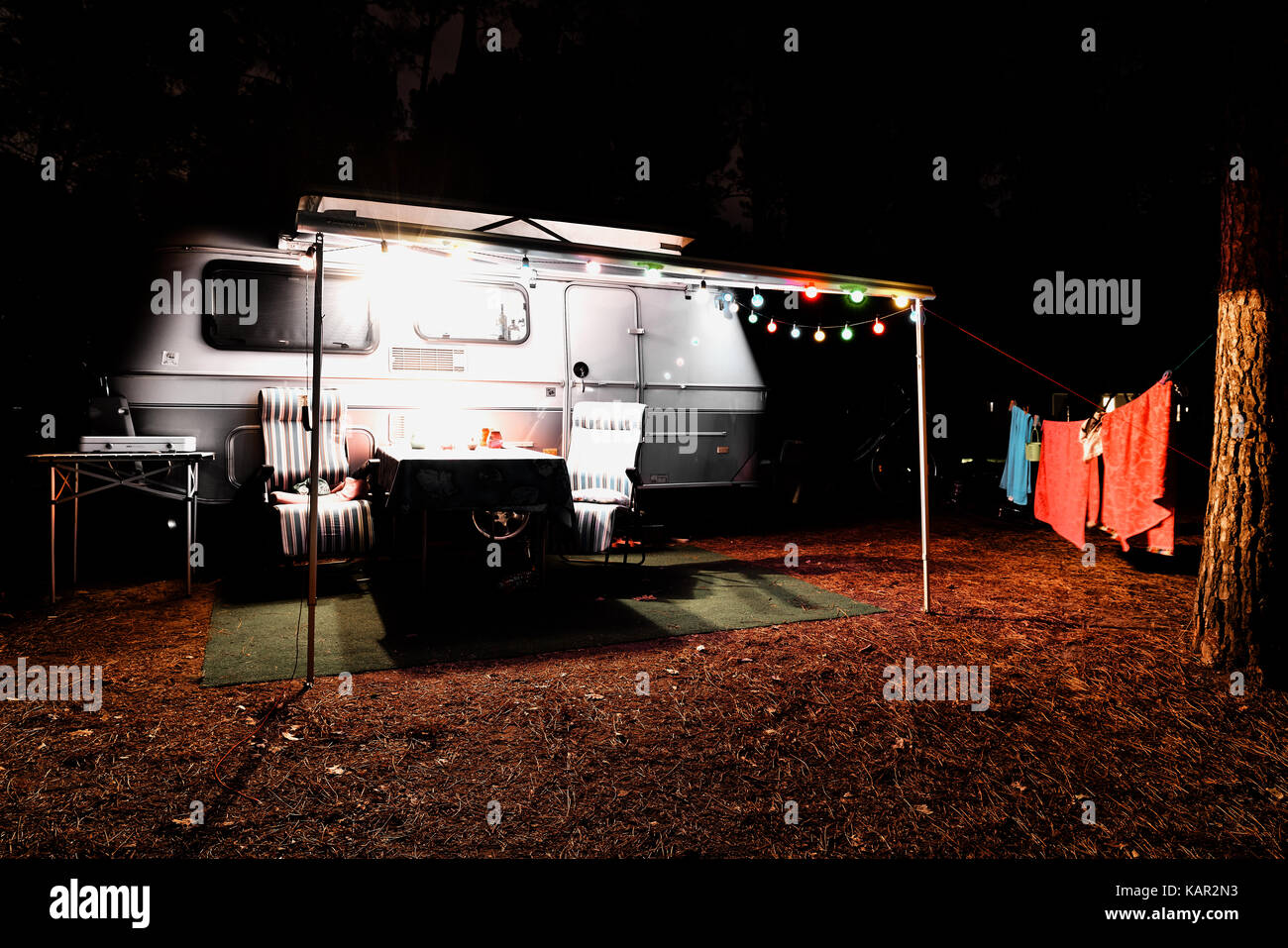 Retro vintage camping caravan trailer at night in a forest with lights ...