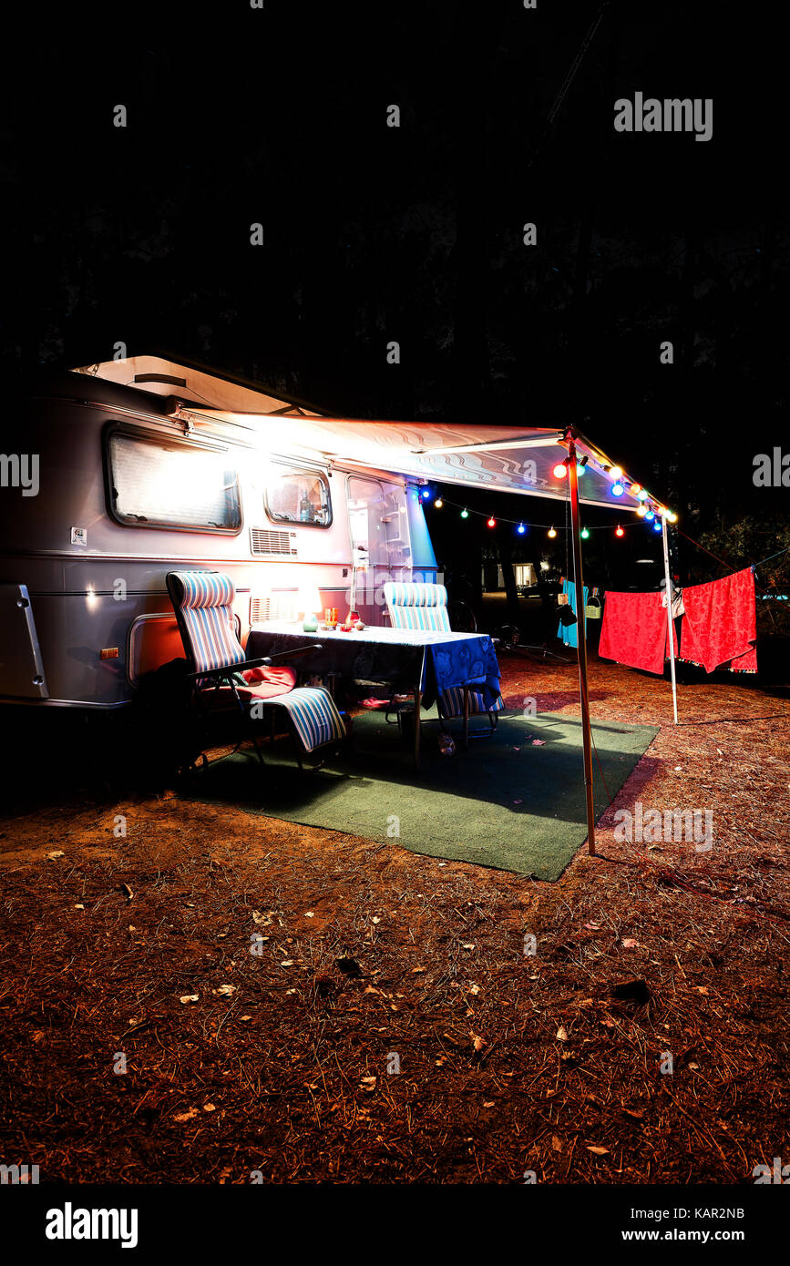 Retro vintage camping caravan trailer at night in a forest with lights ...
