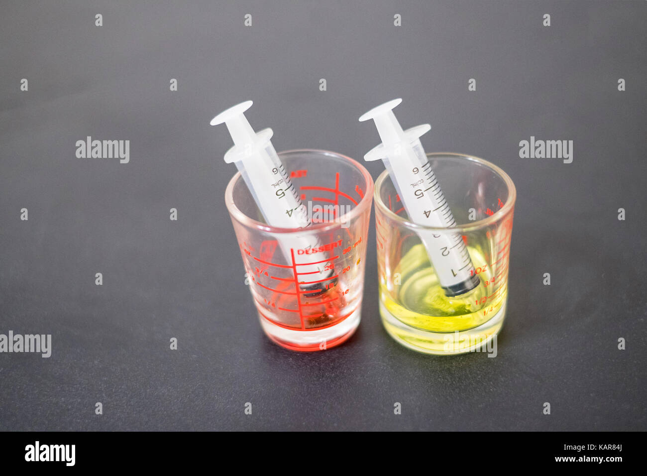 syringe with medicine syrup in a Pharmaceutical glass measuring cup for ...
