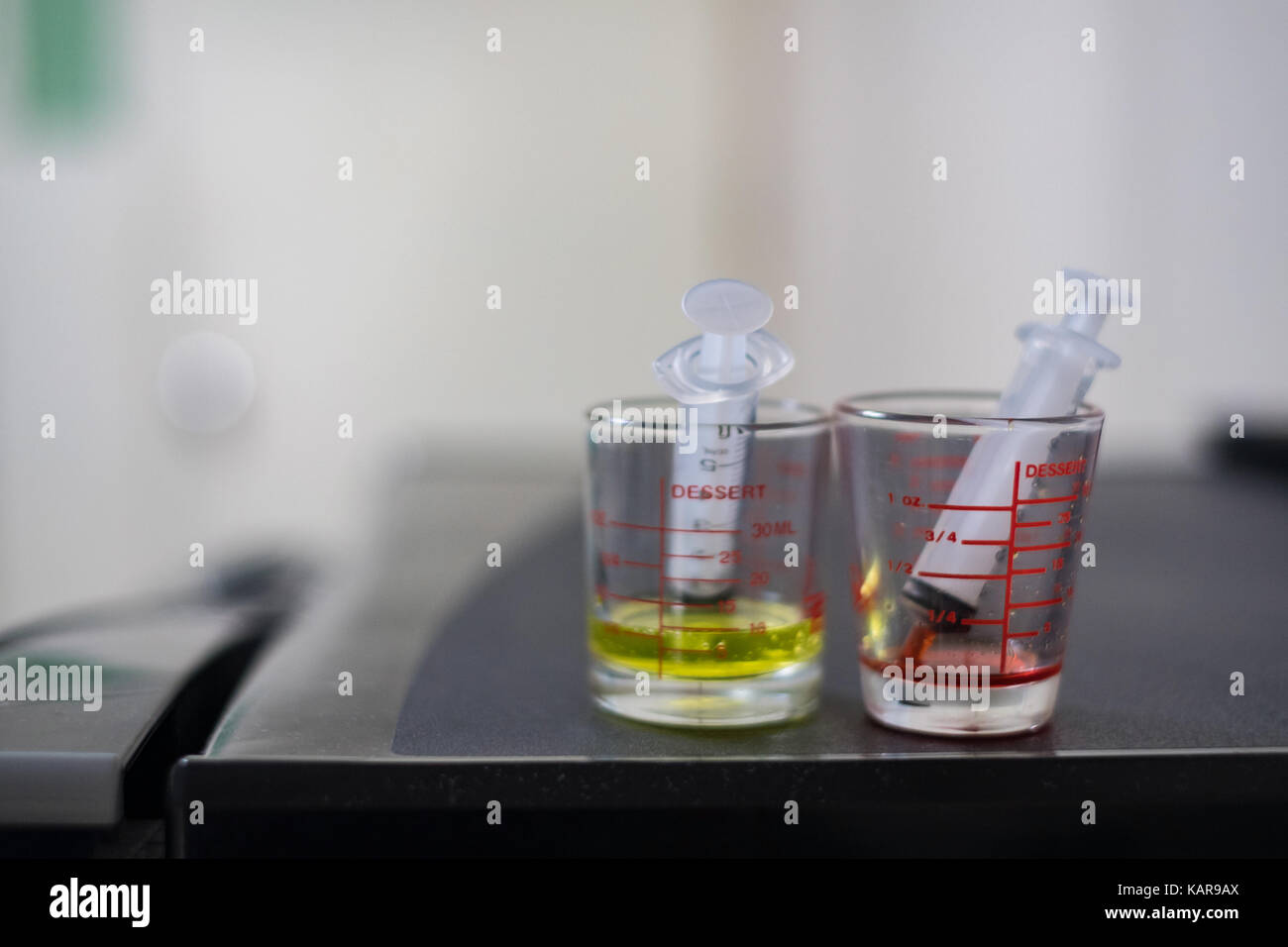 syringe with medicine syrup in a Pharmaceutical glass measuring cup for ...