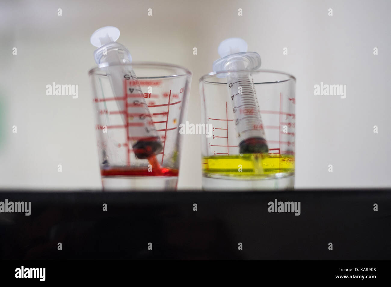 syringe with medicine syrup in a Pharmaceutical glass measuring cup for ...