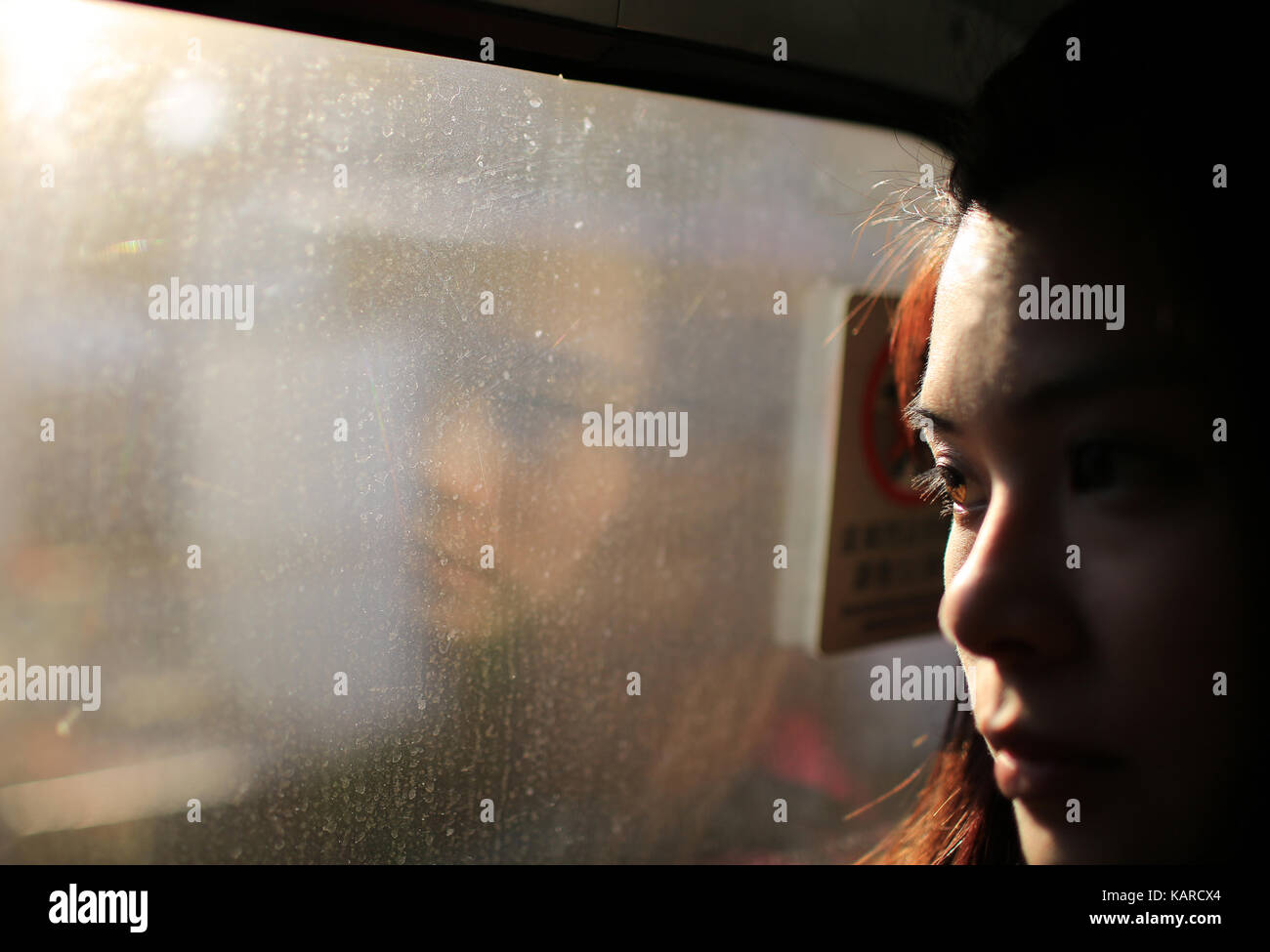 sad girl in the sunlight near train window Stock Photo - Alamy