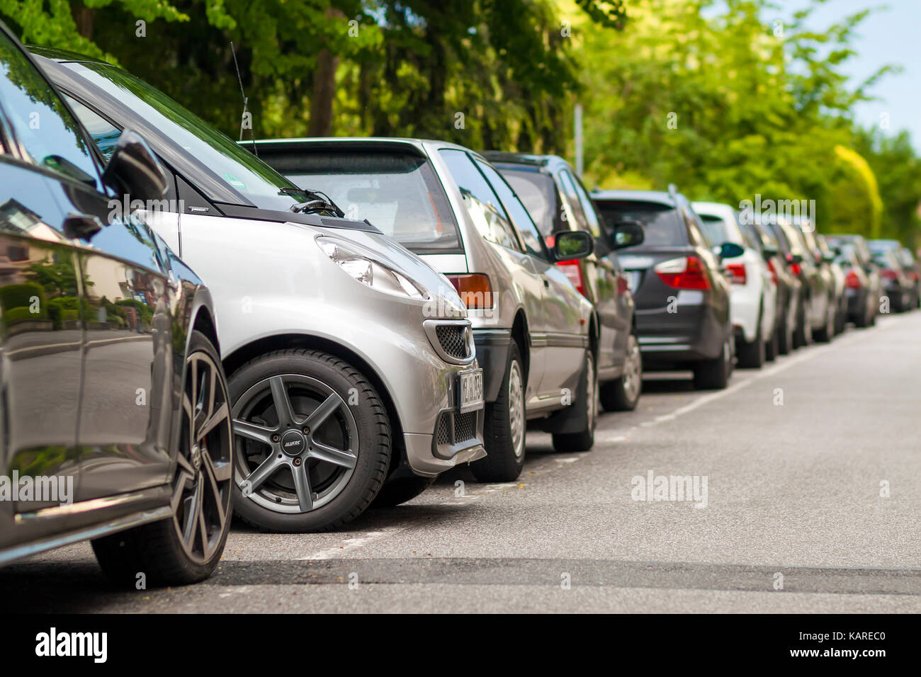 Rows of cars parked on the roadside in residential district. Small car ...