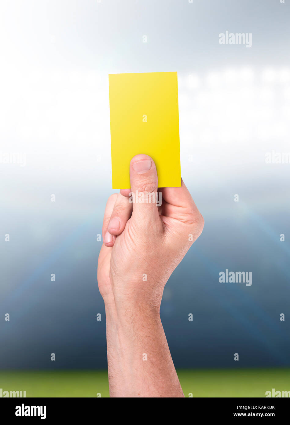 A male sports referee or umpire hand holding a yellow card up in the ...