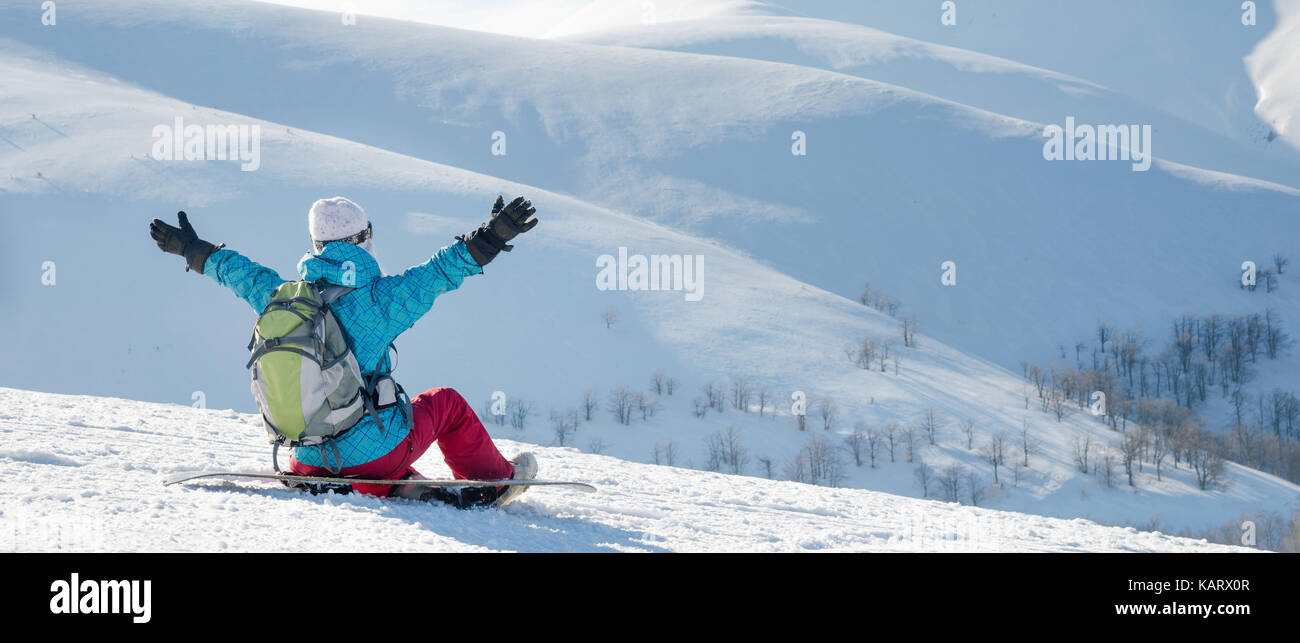 Young woman with snowboard sitting on the slope of hill Stock Photo - Alamy