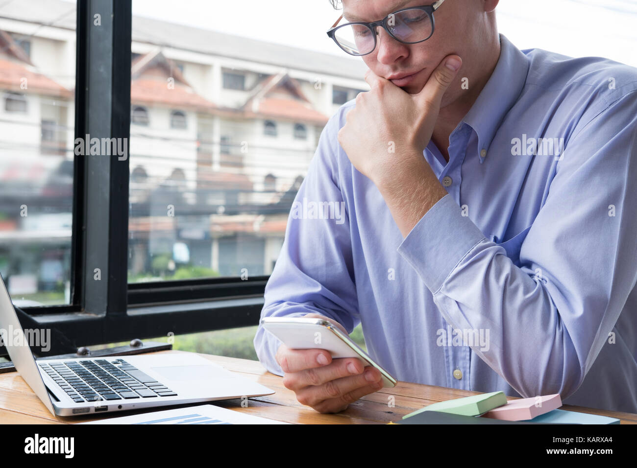 thoughtful businessman use mobile phone at workplace. young man texting ...