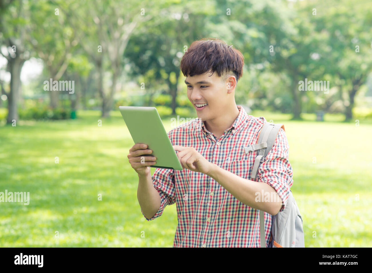 Male asian student using digital tablet in park Stock Photo - Alamy