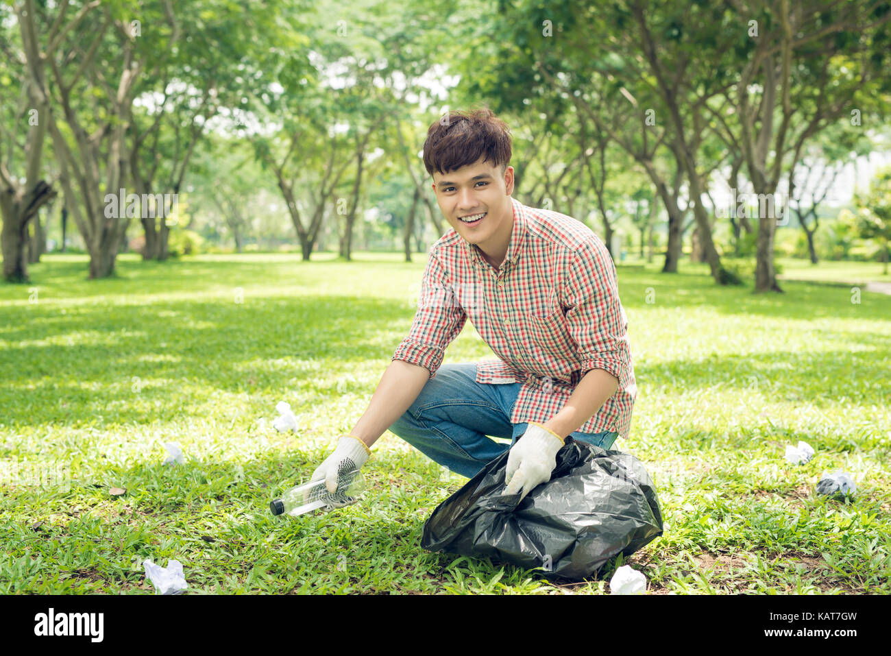 Asian man picking up plastic household waste in park Stock Photo - Alamy